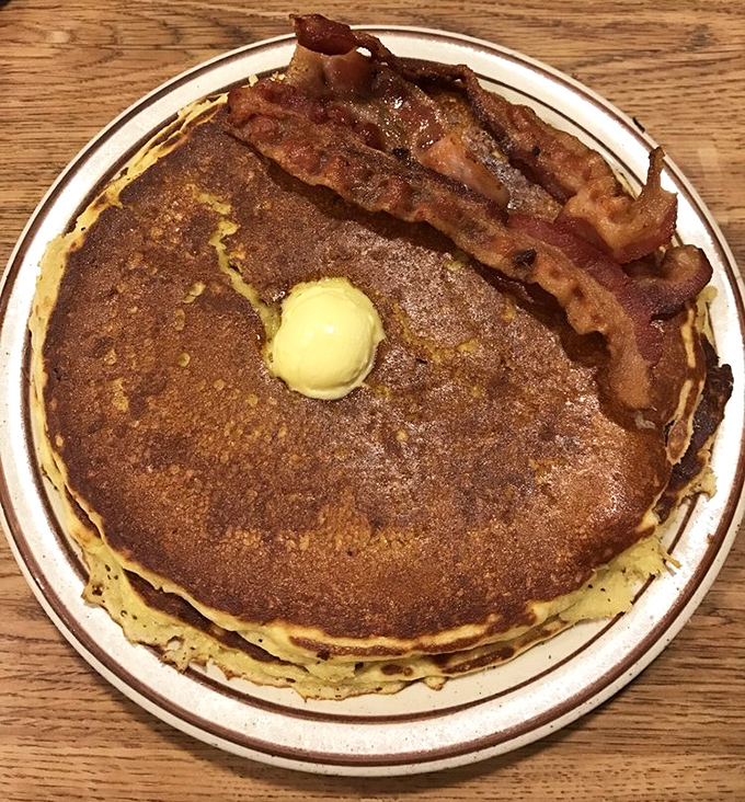 That perfect pancake golden-brown that no Instagram filter can improve. The butter pat melts with purpose, and that bacon means business. 