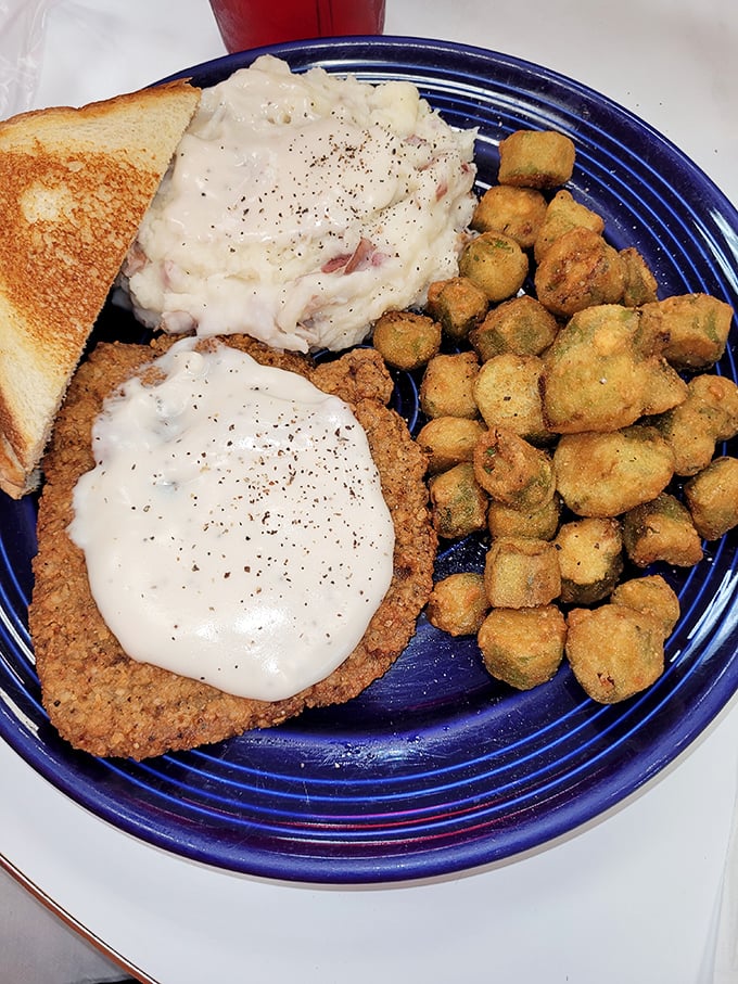 Southern comfort on a blue plate: country fried steak smothered in gravy alongside mashed potatoes and fried okra&mdash;a trifecta of down-home deliciousness.