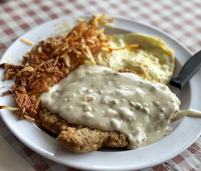 Country-fried steak swimming in creamy gravy alongside crispy hash browns. The kind of breakfast that makes you want to buy a rocking chair and overalls.