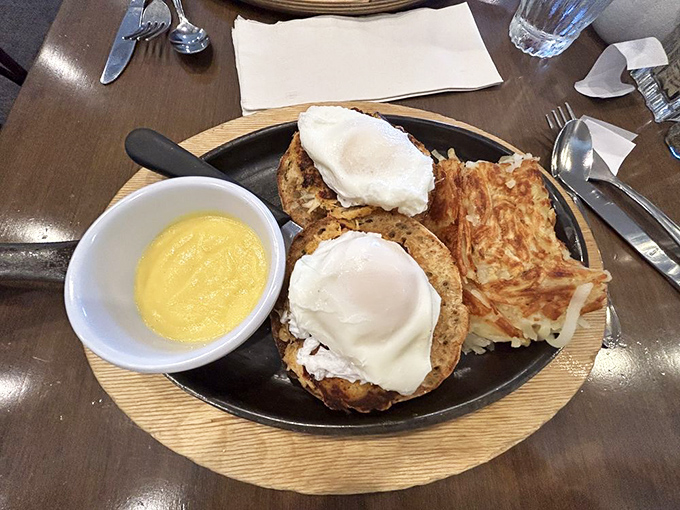 Two perfectly poached eggs perched atop their English muffin thrones. The hash browns stand guard like crispy sentinels.