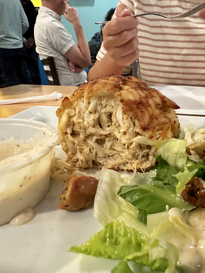 The cross-section reveals the truth &ndash; this is almost entirely crab meat, held together by what seems like wishful thinking and a prayer. Maryland perfection on a plate.