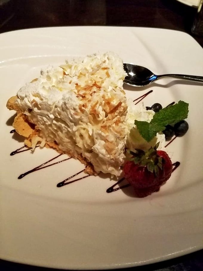 Towering cream pie that defies both gravity and restraint, garnished with berries to help you pretend there's something healthy happening here.