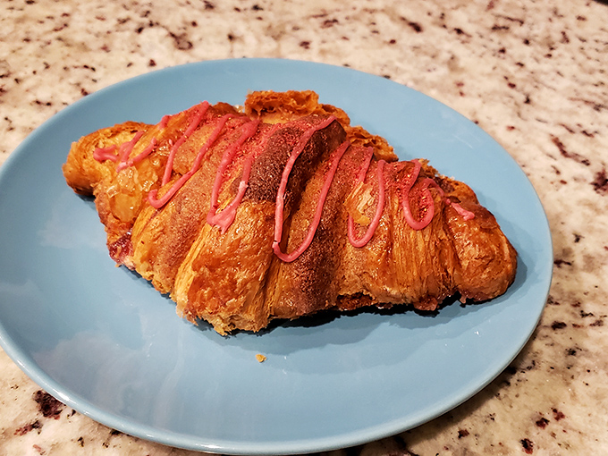 This isn't just a croissant&mdash;it's butter architecture, a flaky monument to French technique with a pink drizzle that says, "I'm fancy, but I don't take myself too seriously."