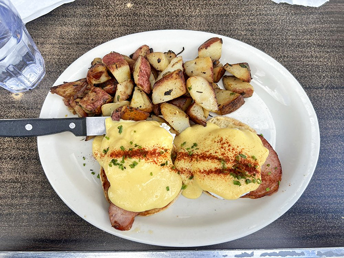 Golden potatoes flank eggs Benedict like loyal bodyguards protecting a celebrity of brunch cuisine. The hollandaise sauce deserves its own IMDb page.