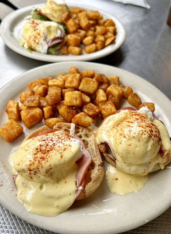 Eggs Benedict: where hollandaise sauce flows like liquid gold over perfectly poached eggs. Those home fries aren't just a side—they're co-stars.