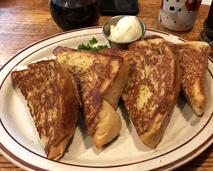 Golden-brown French toast that's achieved that mythical balance – crispy edges, custardy center, and a small scoop of butter slowly melting into breakfast nirvana.