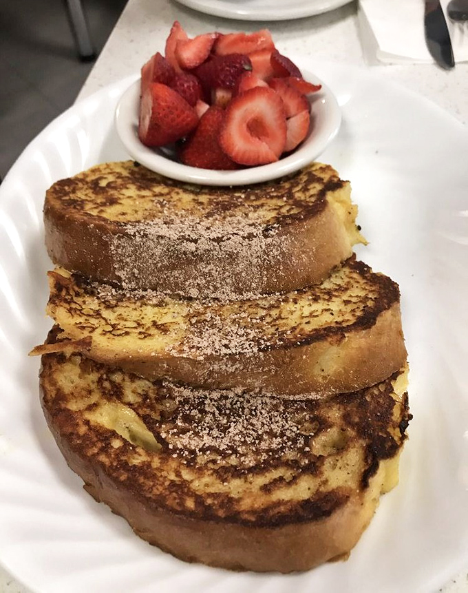 French toast so thick it could double as a mattress, dusted with powdered sugar and served with fresh strawberries that taste like they were picked this morning.