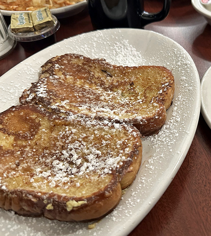 French toast that's dressed for success with a gentle snowfall of powdered sugar. Each slice a testament to the virtue of simplicity done perfectly.