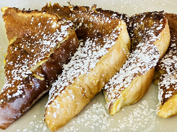 French toast that's achieved the impossible trifecta: crispy edges, custardy center, and enough powdered sugar to make your dentist wince approvingly.