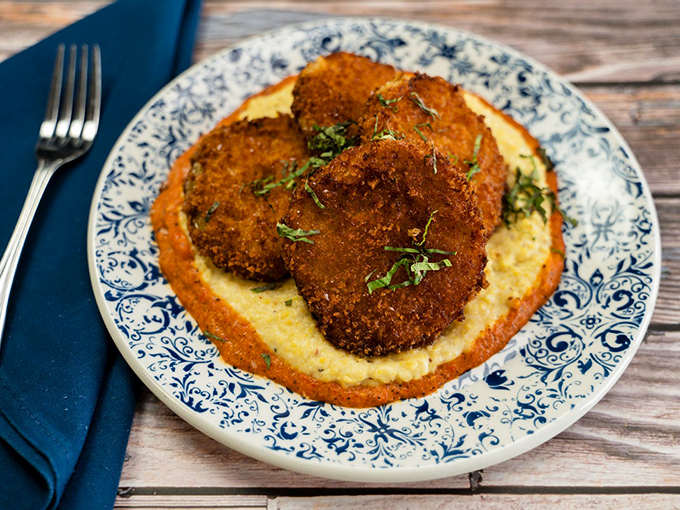 Fried green tomatoes resting on creamy grits&mdash;proof that sometimes the best things in life are those that refuse to ripen too quickly.
