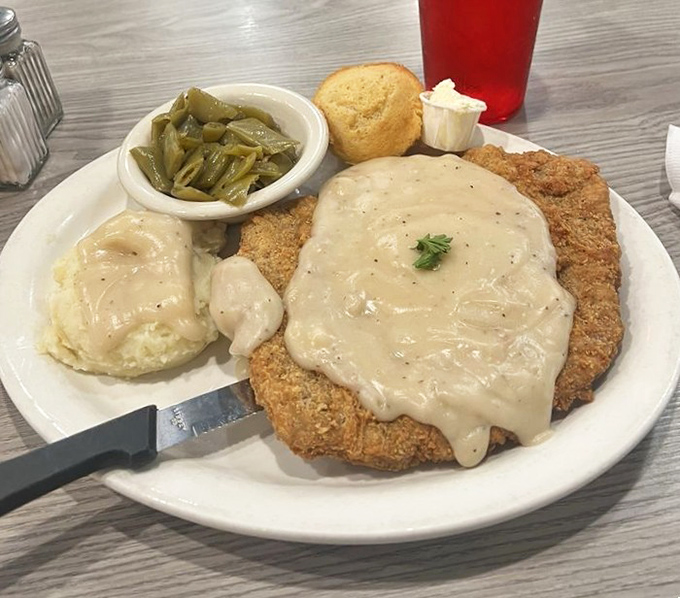 Country fried steak swimming in creamy gravy alongside mashed potatoes and green beans. The holy trinity of Southern comfort that makes diets weep and cardiologists wince.