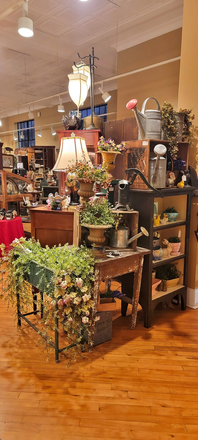 Nature meets nostalgia in this garden-themed vignette, where vintage watering cans and weathered tables create an indoor oasis of rustic charm.