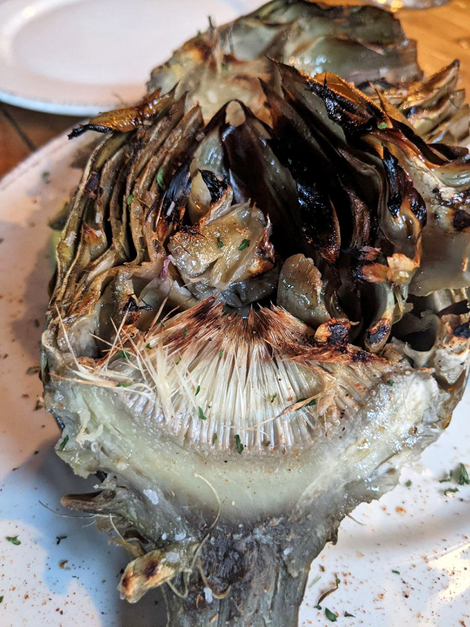 The grilled artichoke&mdash;nature's edible puzzle&mdash;transformed by fire and seasoning into something that makes you forget you're eating a vegetable.
