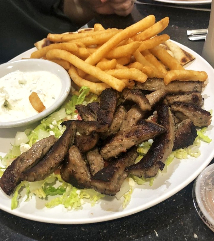 Seasoned gyro meat resting on a bed of crisp lettuce, accompanied by golden fries and tzatziki&mdash;proof that Sterling, Virginia knows its Mediterranean flavors.