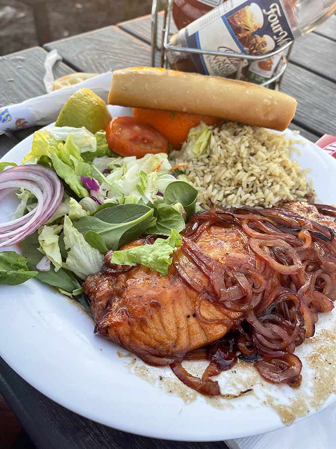 Salmon that didn't die in vain. Caramelized onions cascade over perfectly cooked fish alongside rice pilaf and greens—a balanced seafarer's delight.