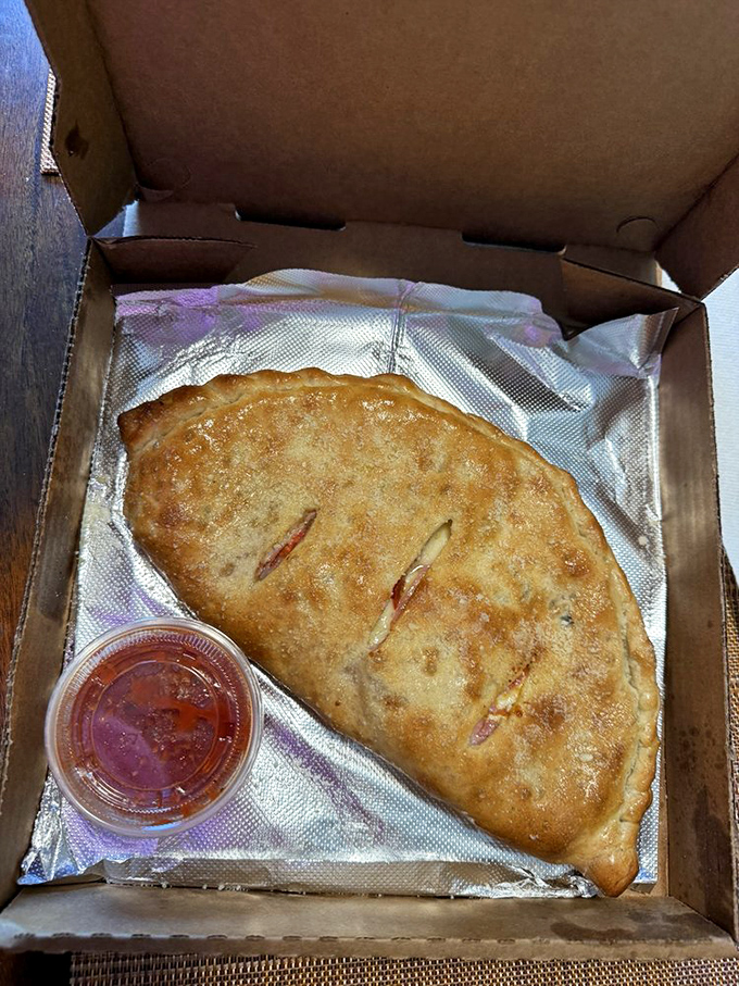 This calzone emerges from the oven like a golden pillow stuffed with molten cheese dreams.