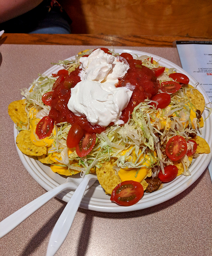 Nachos that require a structural engineer's approval. That mountain of cheese, salsa, and sour cream is what happens when "a little extra" becomes policy.