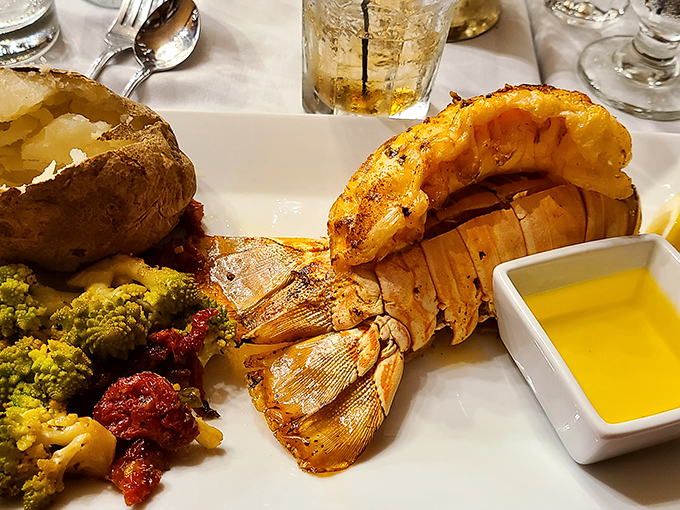 The lobster tail arrives like royalty on a plate, accompanied by a baked potato and colorful vegetables &ndash; Neptune's treasure meets landlubber's delight.