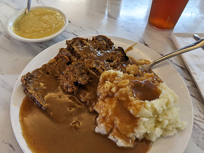 Meatloaf that doesn't apologize for being meatloaf. This isn't your "modern interpretation"—it's the genuine article, complete with gravy lake and mashed potato island.