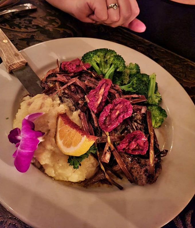 A perfectly seared steak adorned with crispy leeks and a vibrant orchid. Even the broccoli looks like it's having a good time at this party.