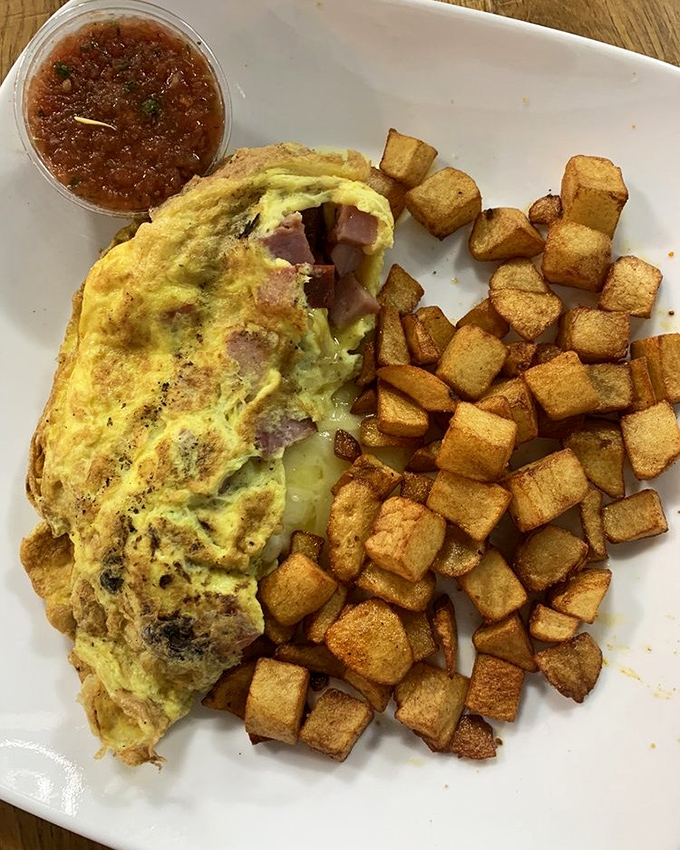 The omelet that launched a thousand satisfied sighs, paired with home fries so perfectly crisp they deserve their own fan club.