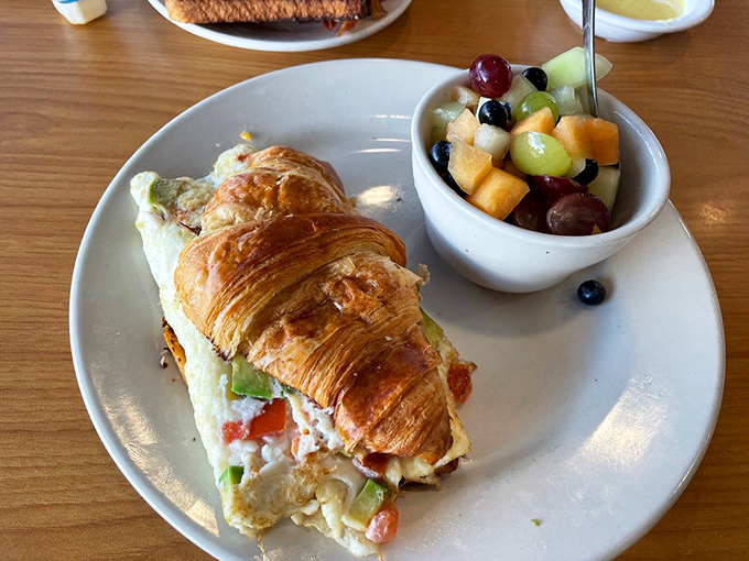 A croissant sandwich that puts ordinary breakfast sandwiches to shame, paired with fresh fruit that almost makes you feel virtuous. Almost.