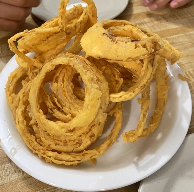 Onion rings stacked higher than my college textbooks, and infinitely more satisfying. Crispy, golden, and unapologetically indulgent.