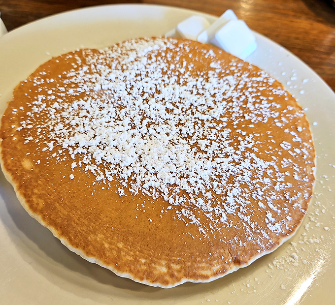 This isn't just any pancake&mdash;it's a golden canvas dusted with powdered sugar, awaiting its maple destiny.