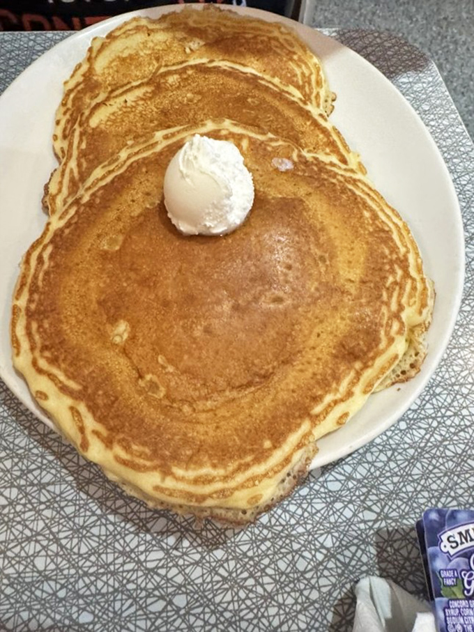 Pancakes so perfectly golden they deserve their own spotlight, topped with a cloud of butter that's slowly creating a heavenly puddle.