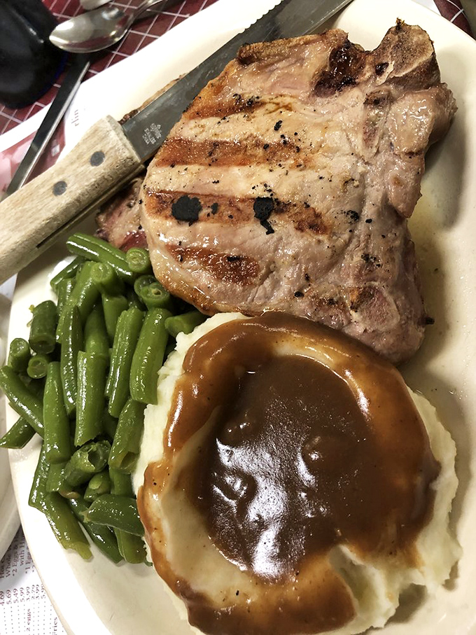 This perfectly grilled pork chop arrives with sides that transform dinner into a memorable celebration.