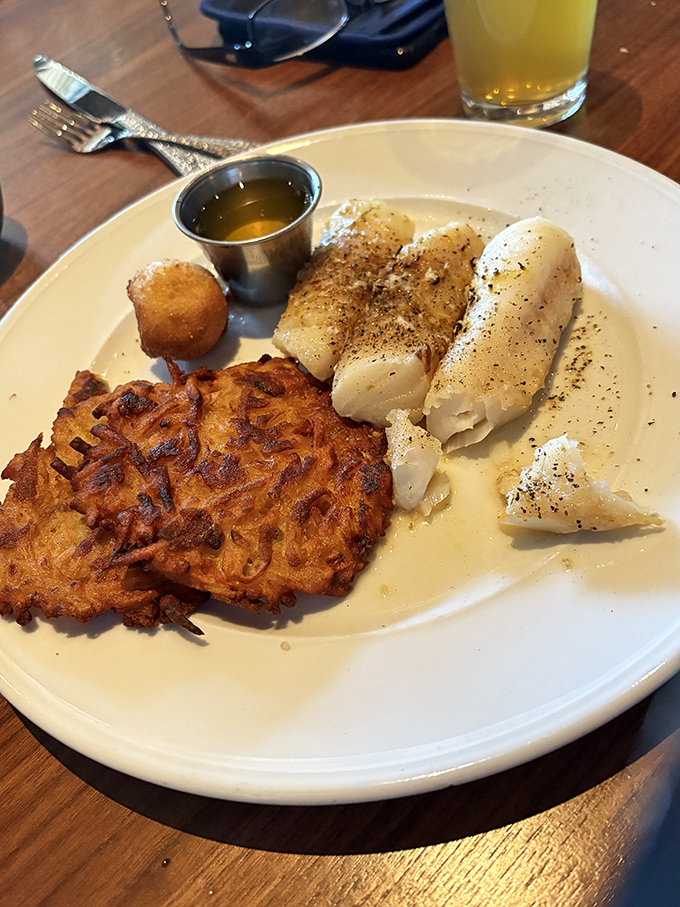 The humble potato achieves its highest calling in these crispy-edged pancakes, sharing the plate with delicate fish that flakes at the mere suggestion of a fork.