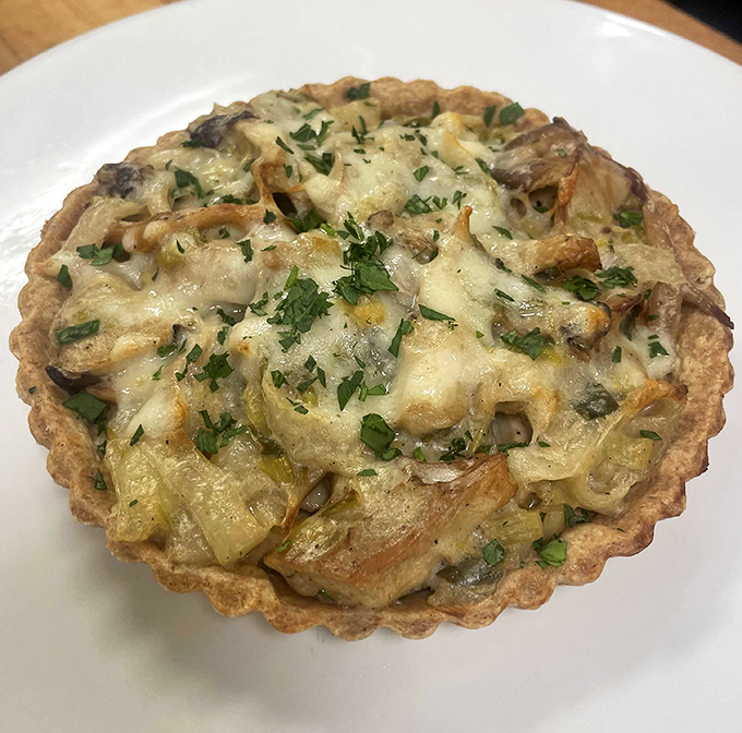 This savory tart is what happens when buttery pastry meets creamy filling. Topped with melted cheese and fresh herbs, it's quiche that demands respect.