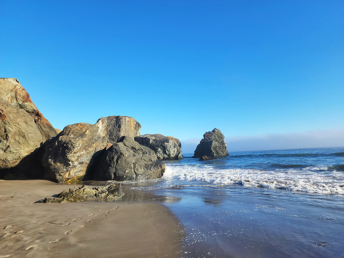 Massive rock formations guard this section of beach like nature's own sculpture garden, where waves have been the patient artists for millennia.