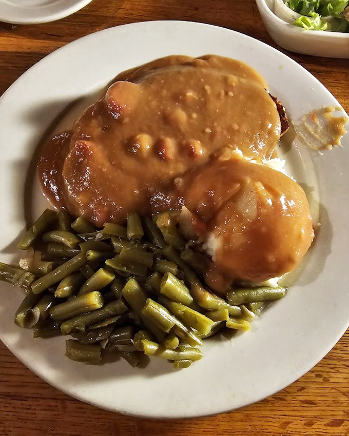 Comfort food royalty: meatloaf draped in savory gravy alongside fresh green beans that haven't forgotten they came from an actual garden.