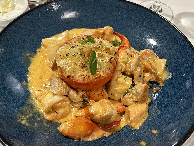 A seafood medley swimming in creamy sauce with a broiled tomato island&mdash;the kind of dish that makes you consider drinking the remaining sauce when no one's looking.