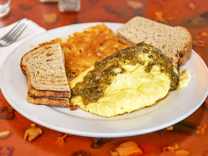 An omelet that wears its southwestern heritage proudly, draped in vibrant salsa verde like a delicious edible flag of flavor.