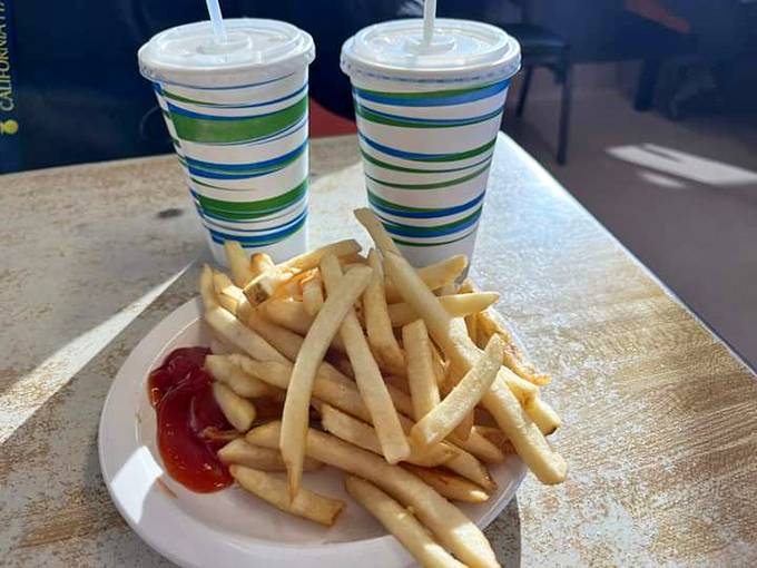 Golden fries and striped cups that transport you back to simpler times. The kind of combo that makes you wonder why you ever bothered with truffle fries.