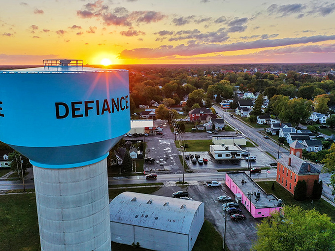 The water tower stands sentinel at sunset, proudly displaying the town's name while the sky puts on a color show that no Instagram filter could improve.