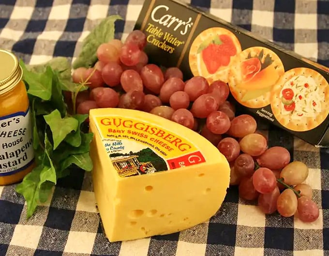 Guggisberg Baby Swiss with grapes and crackers&mdash;the holy trinity of snacking. This cheese board isn't just a meal, it's a statement.