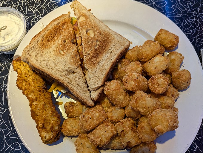 Golden-brown tater tots that achieve that mythical balance—crispy exterior giving way to fluffy potato interior—served alongside a perfectly toasted sandwich.
