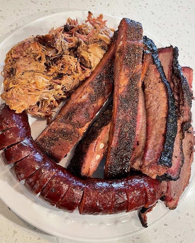 The holy trinity of Texas barbecue: brisket with that perfect smoke ring, pulled pork that surrenders at the touch, and sausage that snaps with attitude.
