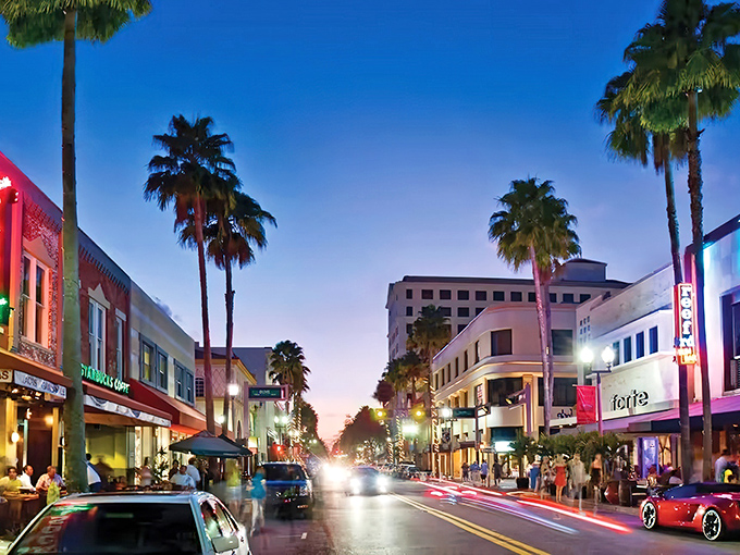 Palm trees standing sentinel over a twilight shopping scene. The vibrant nightlife offers a perfect blend of retail therapy and dining options after a day at the beach.