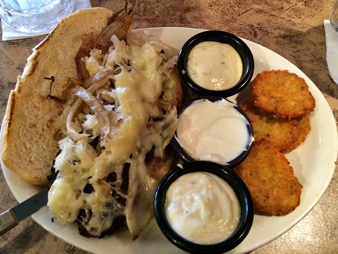 This isn't just a sandwich&mdash;it's architecture. Melted Swiss cascading over bratwurst with three perfect dipping sauces standing at attention.