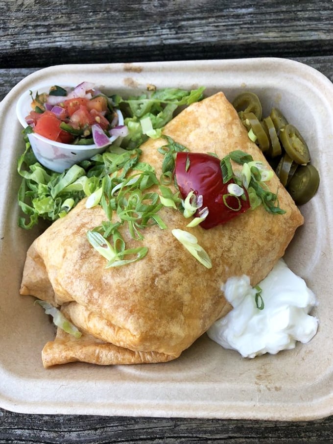 The breakfast burrito: where eggs, cheese, and fresh ingredients unite in tortilla-wrapped bliss. That dollop of sour cream is the chef's kiss.