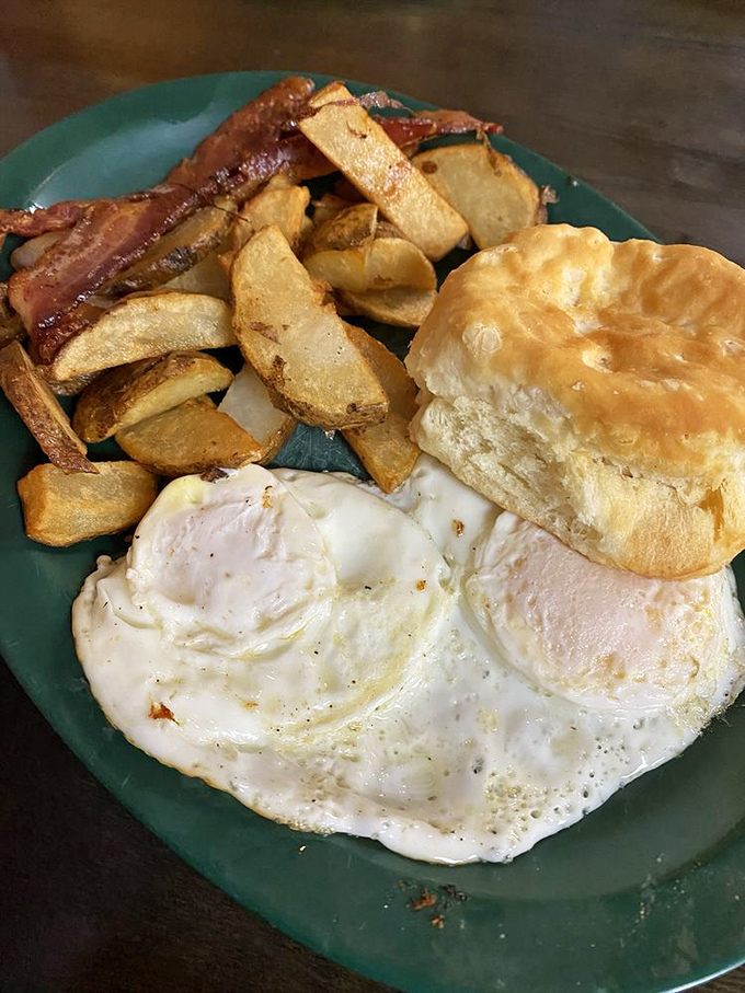 The breakfast holy trinity: perfectly fried eggs, golden hash browns, and a biscuit that would make your grandmother jealous.