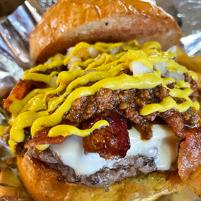 This isn't just a burger&mdash;it's a towering monument to excess with melty cheese, crispy bacon, and that mustard zigzag that says "prepare for delicious chaos."