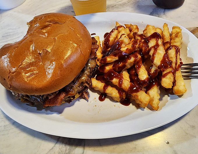 That burger isn't just sitting on the plate&mdash;it's posing for greatness. Those fries with BBQ sauce drizzle? They're the backup singers who could easily be the main act. 