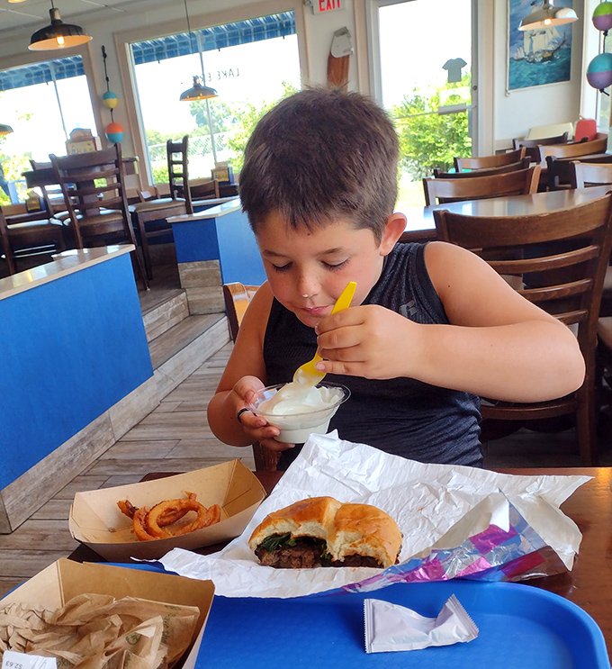 The burger arrives wearing its cheese like a well-earned medal, with onion rings standing guard&mdash;a plate that says "vacation" louder than your Hawaiian shirt.