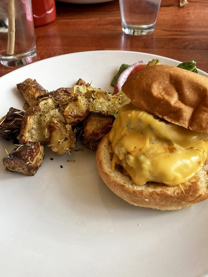 Breakfast sandwich perfection: melted cheese cascading down the sides like it's auditioning for a food commercial, with those rosemary potatoes playing a stellar supporting role.