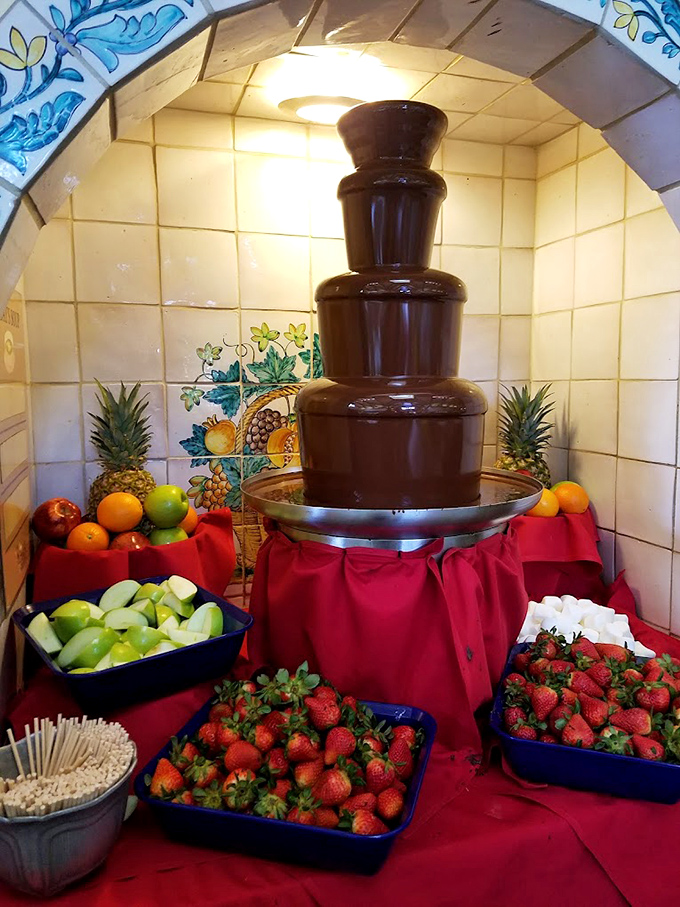 Not just any chocolate fountain – this is the Trevi Fountain of dessert dreams, surrounded by fresh fruit ambassadors waiting for their chocolate baptism.